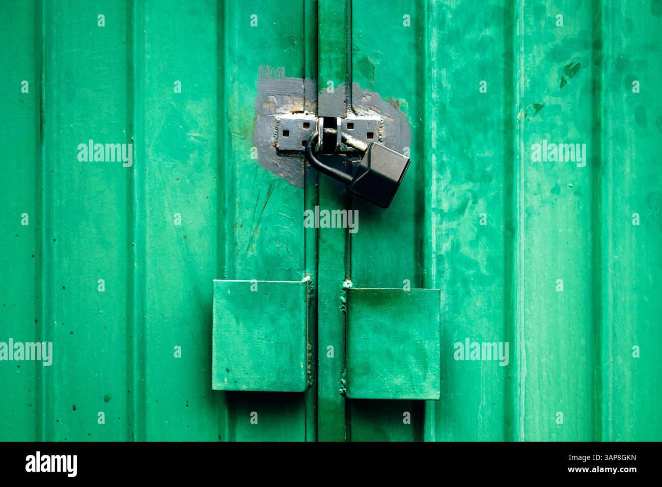 Old green worn metallic garage door with padlock as grunge background ...