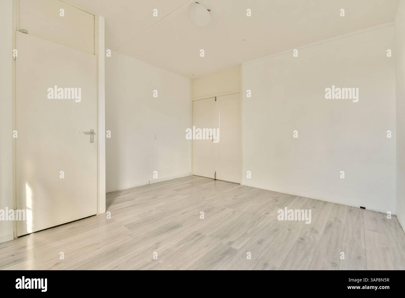 A bright and airy empty room with white walls and simple wooden ...