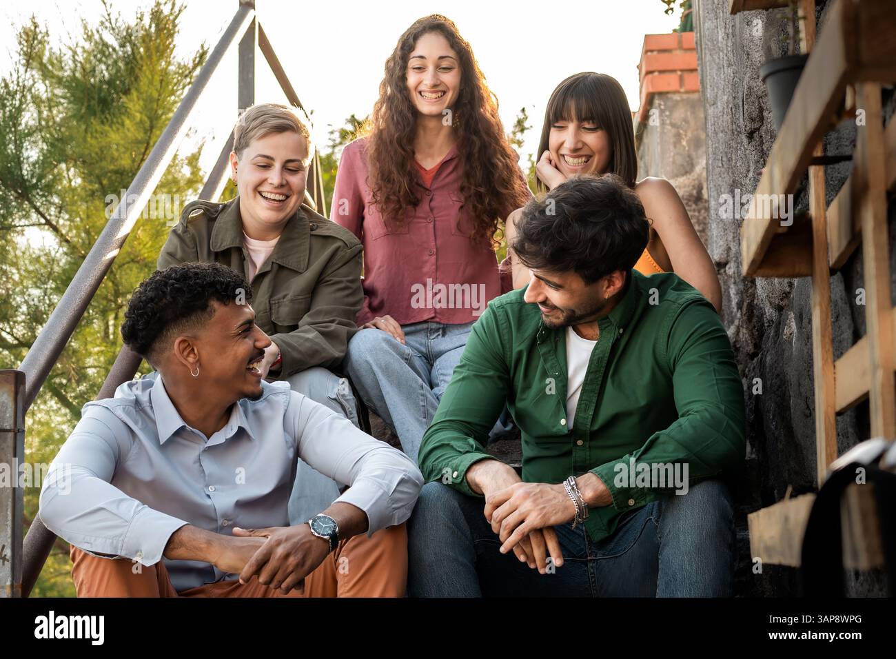 A diverse group of friends interacting and laughing together on outdoor ...