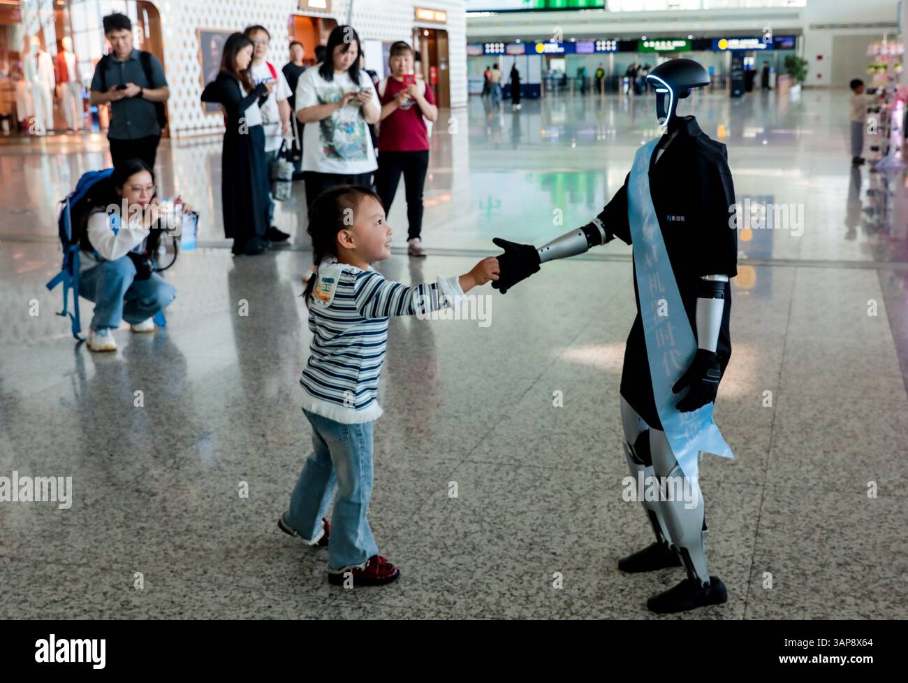 Wuhan,China.15th April 2025. A child shakes hands with at an Unitree G1 ...