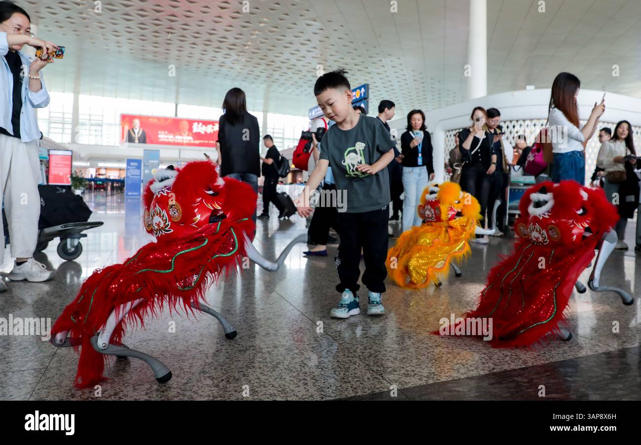 Wuhan,China.15th April 2025. A child interacts with at robot dog ...