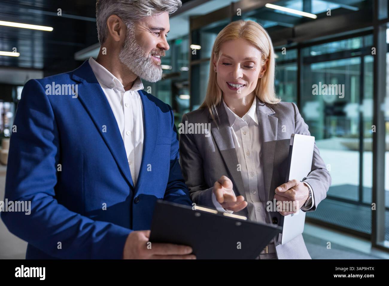 Coworkers standing together in office hall explaining business strategy ...