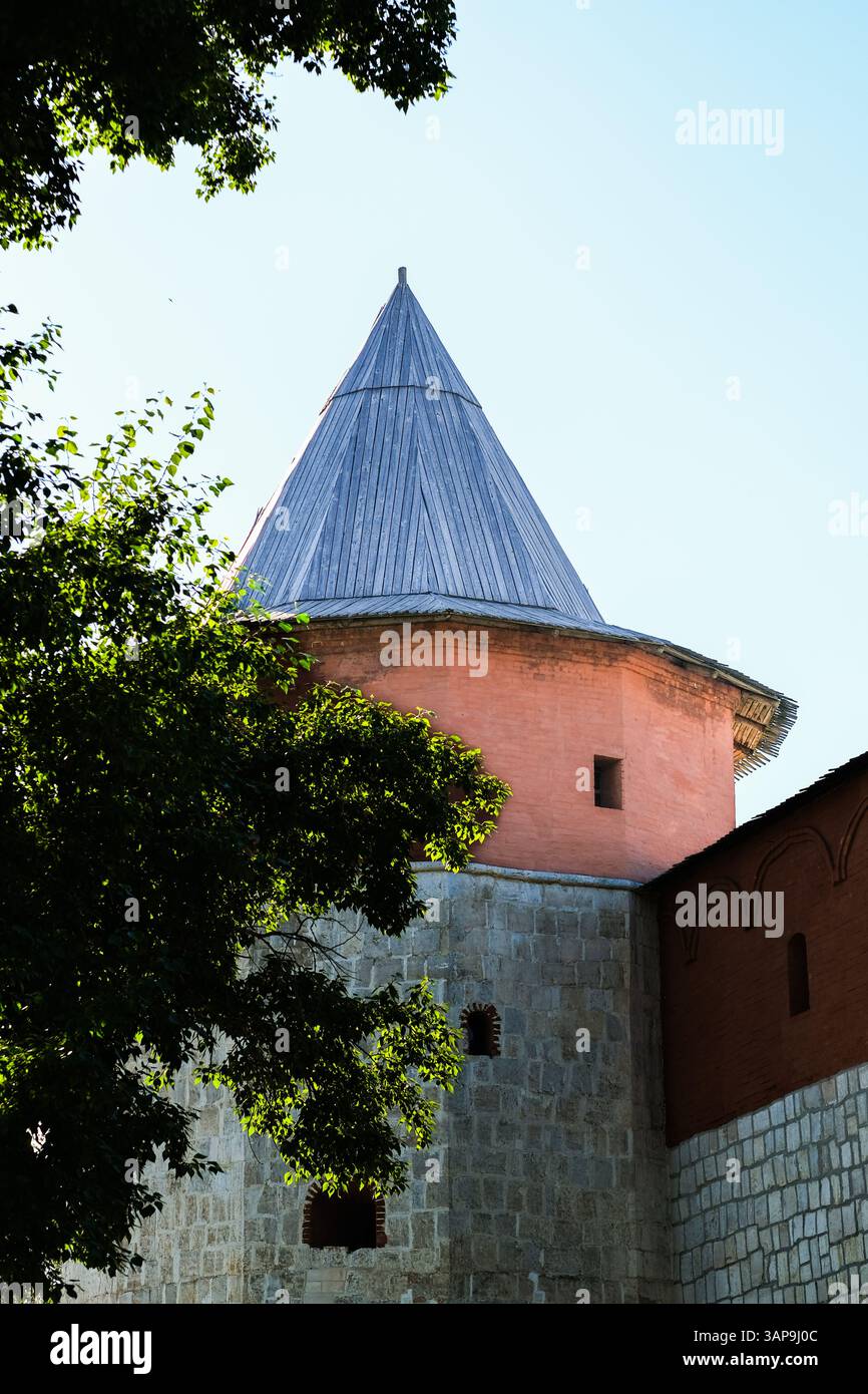 A tall building with a pointed roof and a green tree in front of it ...