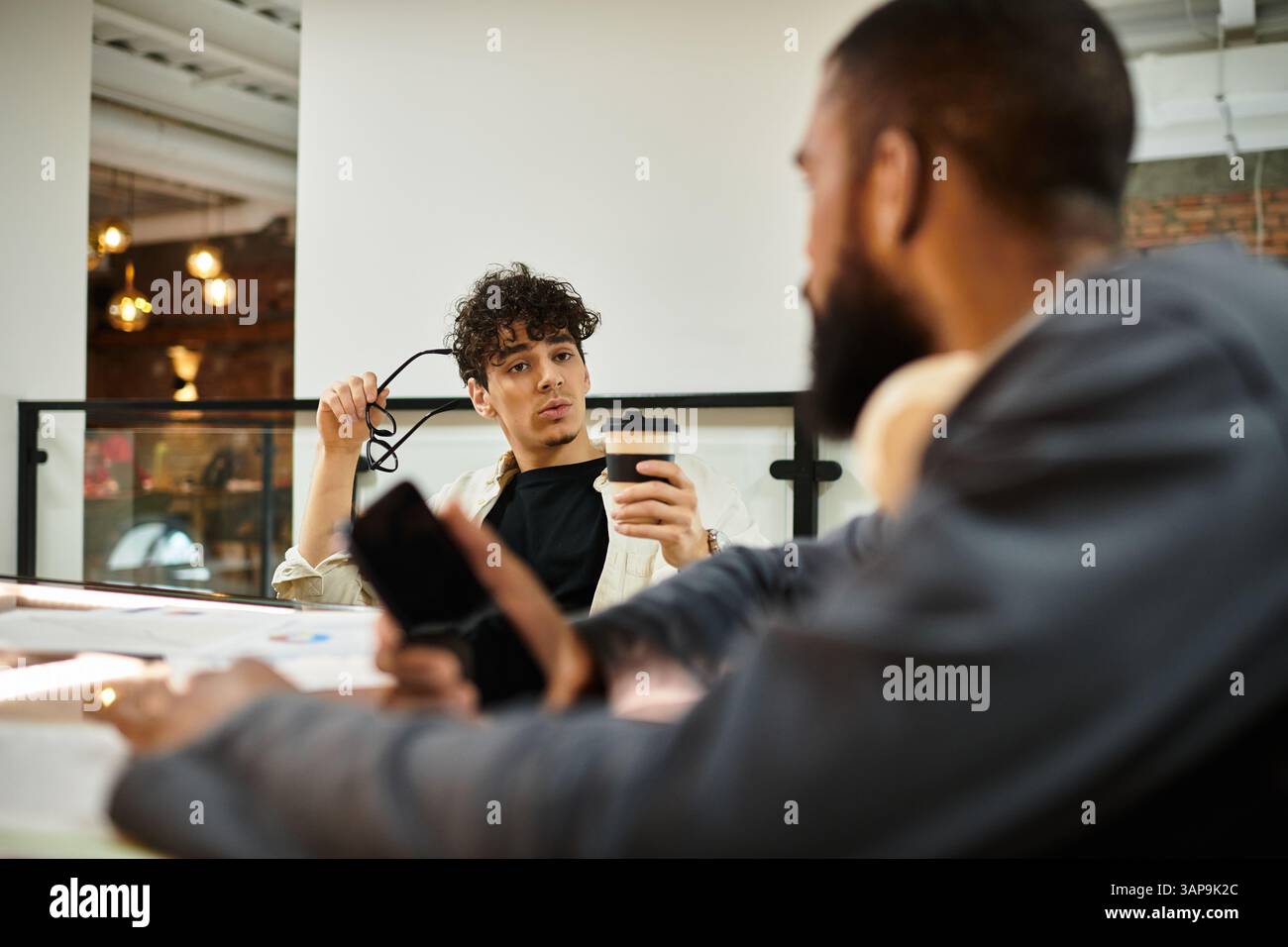 Two professionals chat over drinks in a modern workspace Stock Photo ...