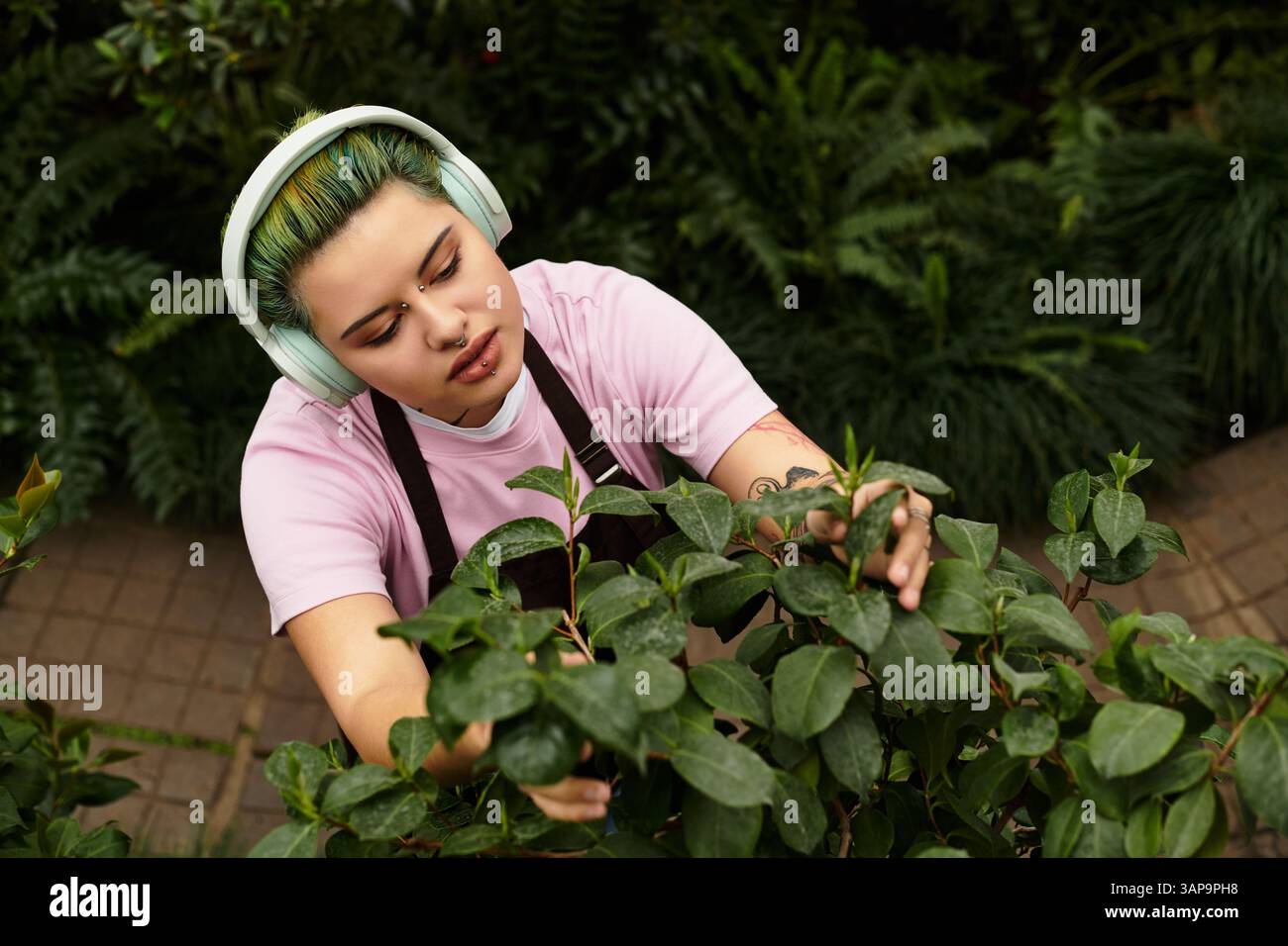 The young woman tends to her plants skillfully while wearing headphones ...