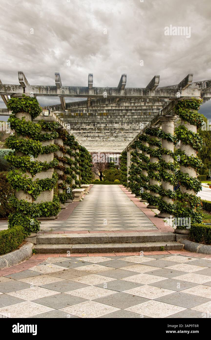 Symmetrical stone pergola with ivy-covered columns in a formal garden ...