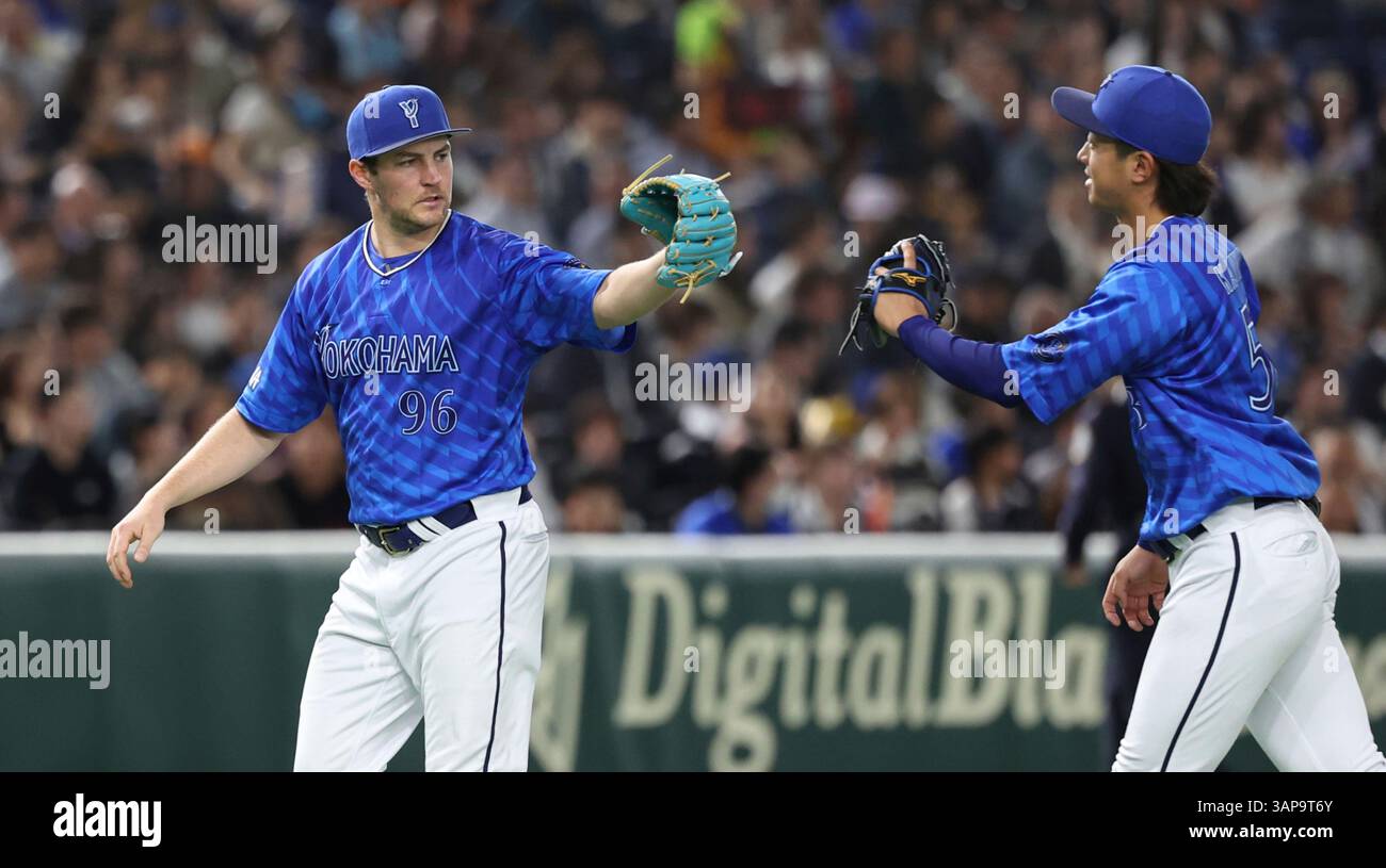 Yokohama DeNA Baystars' starting pitcher Trevor Bauer (L) touches gloves with the center fielder ...