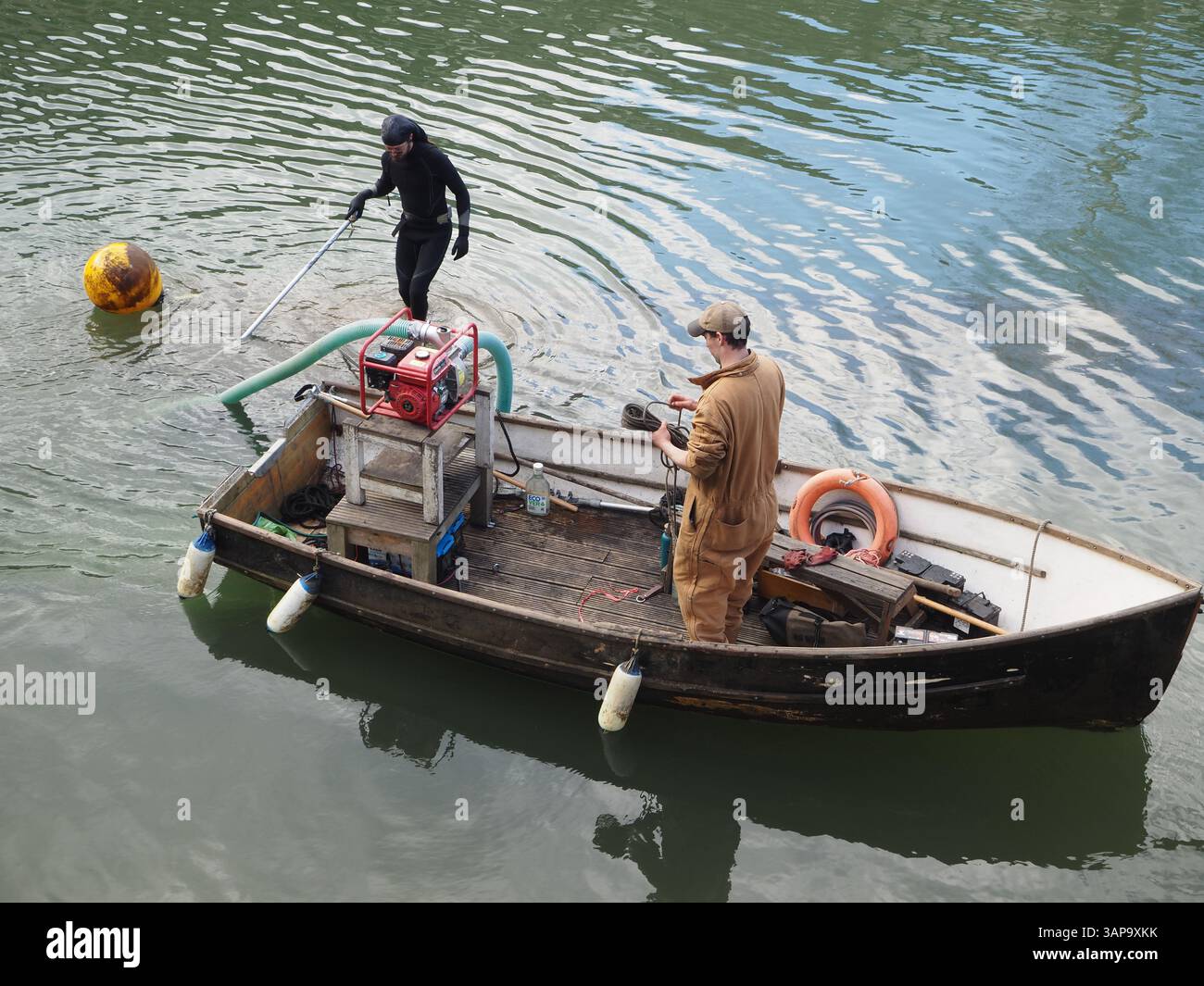 Divers use river water pumped by support boat and manual tools to free ...