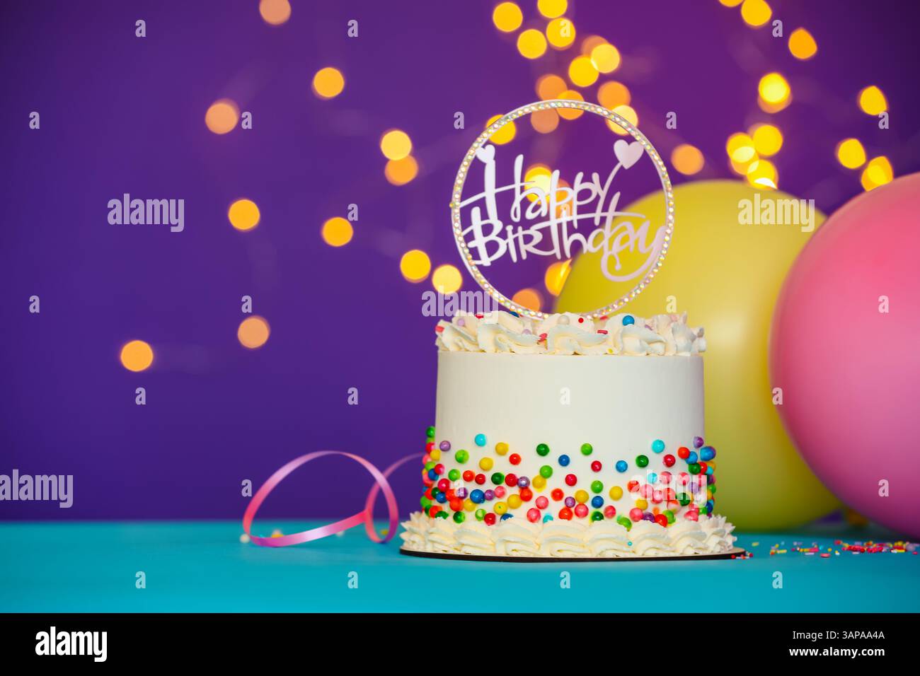 Tasty bento cake with colorful sprinkles, topper and balloons on light ...