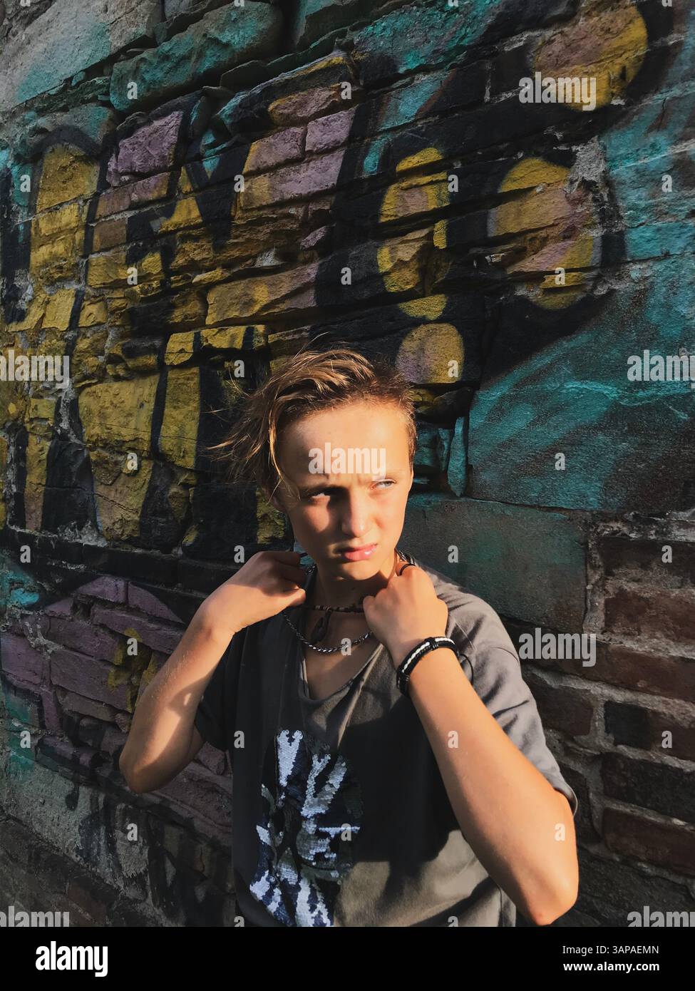 Teen boy stands against a vibrant graffiti-covered wall, showcasing a ...