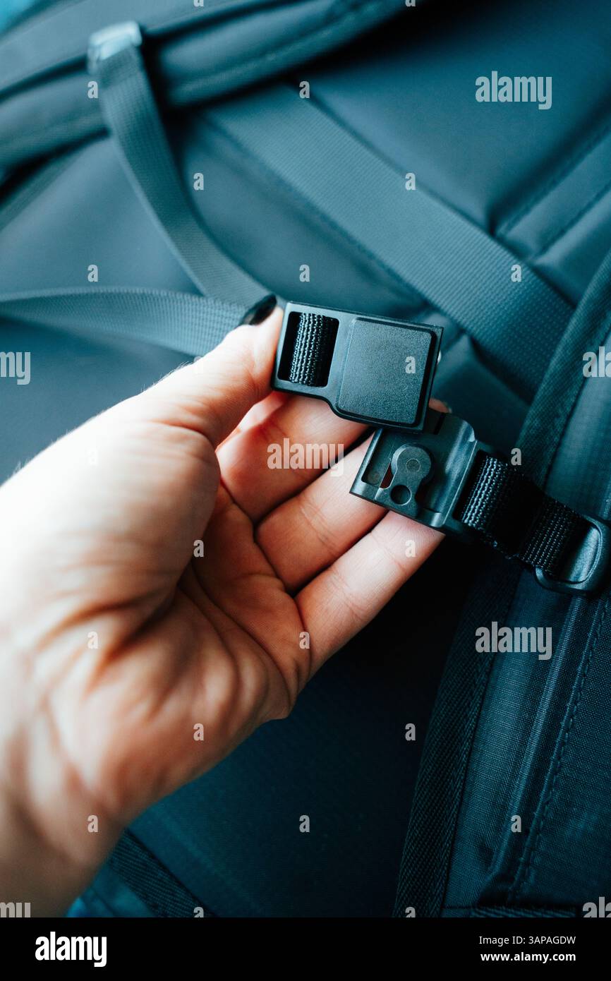 A person is using their hand to grasp the opening strap on a backpack ...
