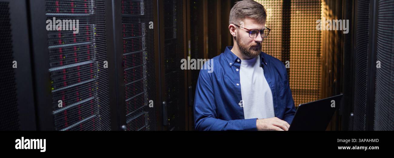 Website header shot of male IT professional working in server room with ...