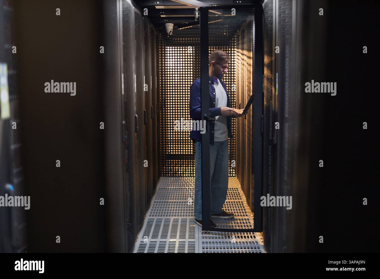 Technician performing routine maintenance in server room with various ...