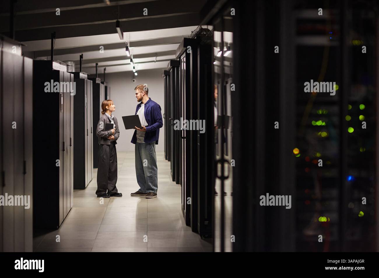 Two individuals discussing work in a well-lit, contemporary data center ...