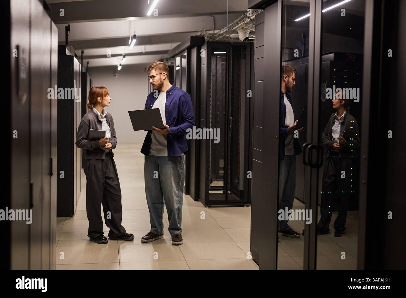 Two IT professionals discussing data management in a modern server room ...