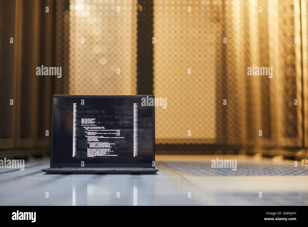 Open laptop displaying lines of code against backdrop of server racks in dim lighting. Scene ...