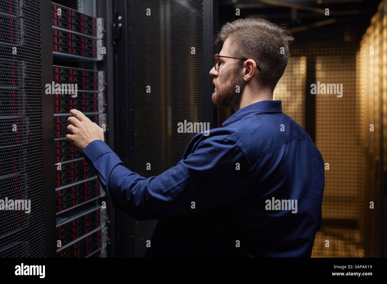 Technician adjusting server hardware in modern data center facility ...