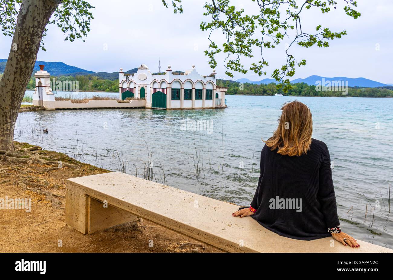 Embarcadero del lago de Banyoles, con una mujer sentada contemplando la ...