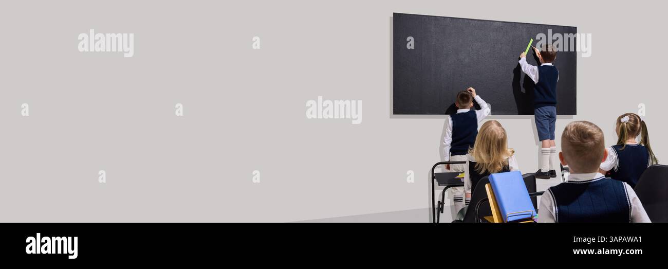 Kids standing at blackboard, solving problem using ruler while ...