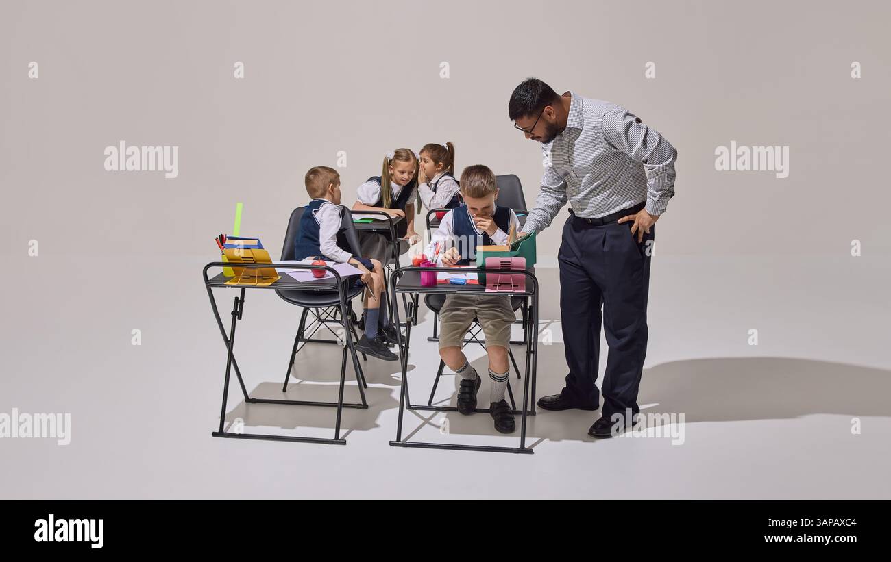 Teacher leading lesson for elementary school pupils, helping in doing ...