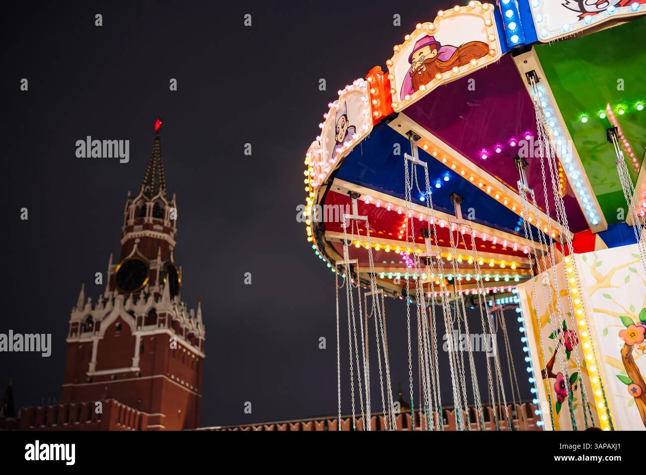 Colorful illuminated carousel spinning in front of Spasskaya Tower in ...