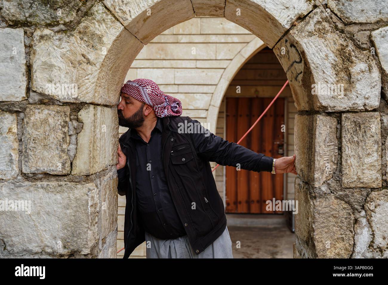An Iraqi Yazidi man kisses holy wall at Lalish mountain valley and ...