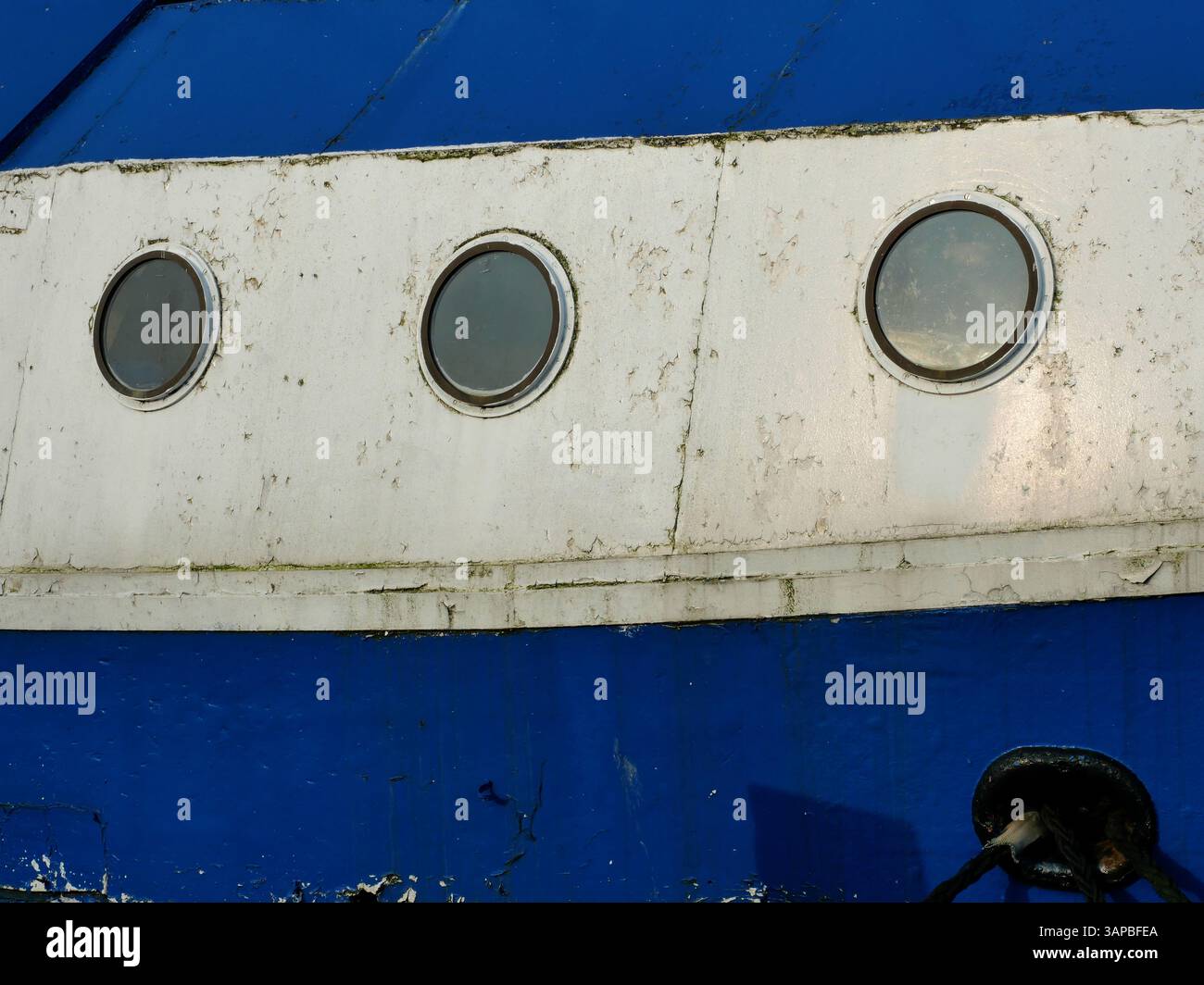 The blue and white ship wall of a fishing boat with portholes looks ...