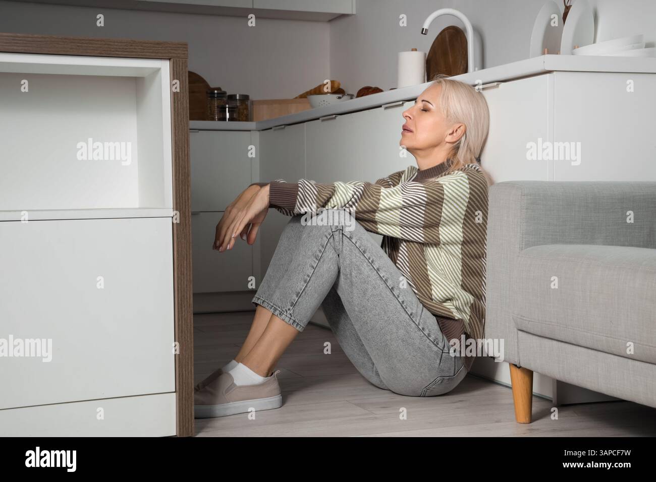 Mature woman having panic attack on floor in kitchen Stock Photo - Alamy