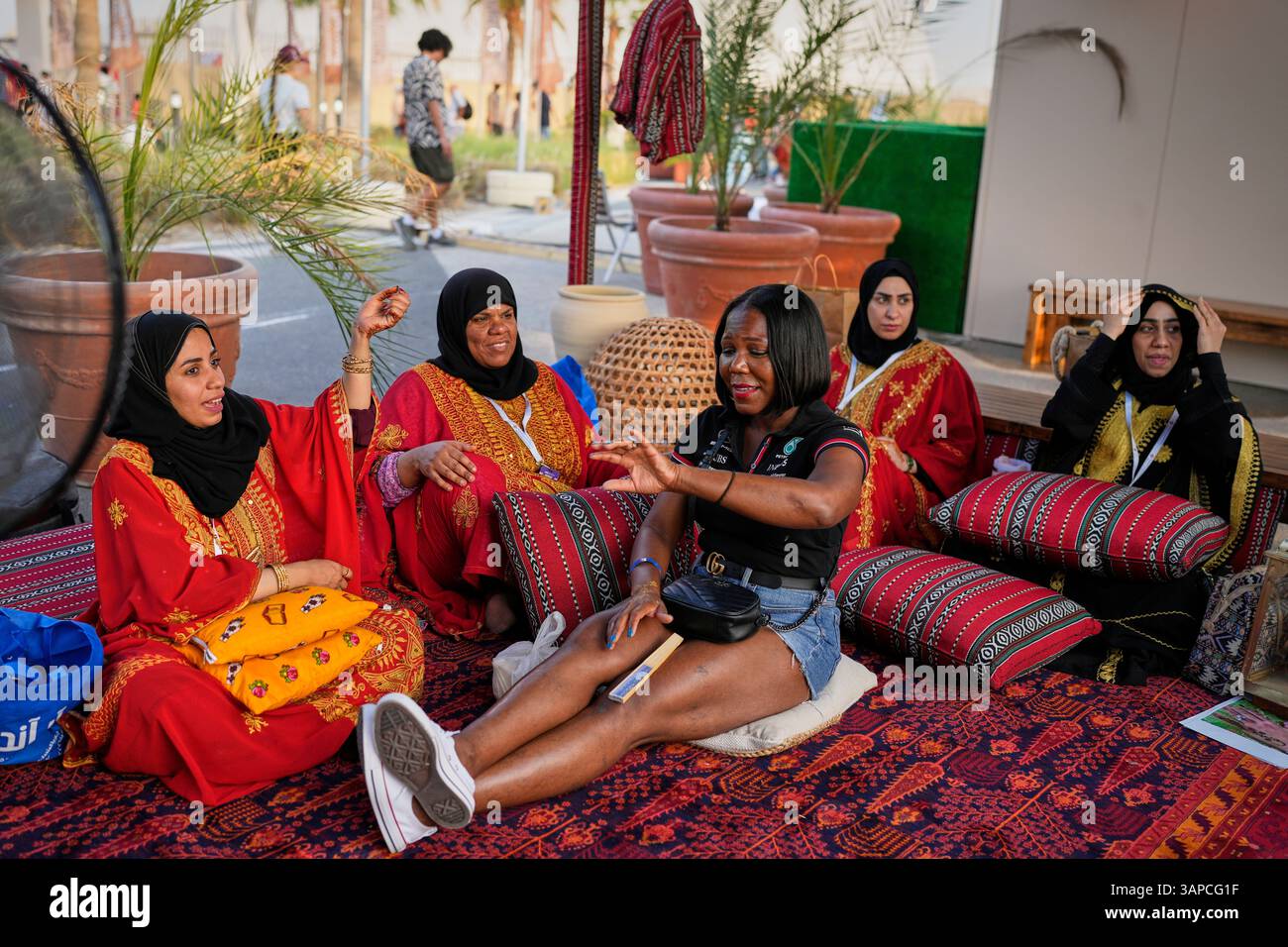 An F1 fan looks at her henna tattoo as Bahraini artists look on, at the ...