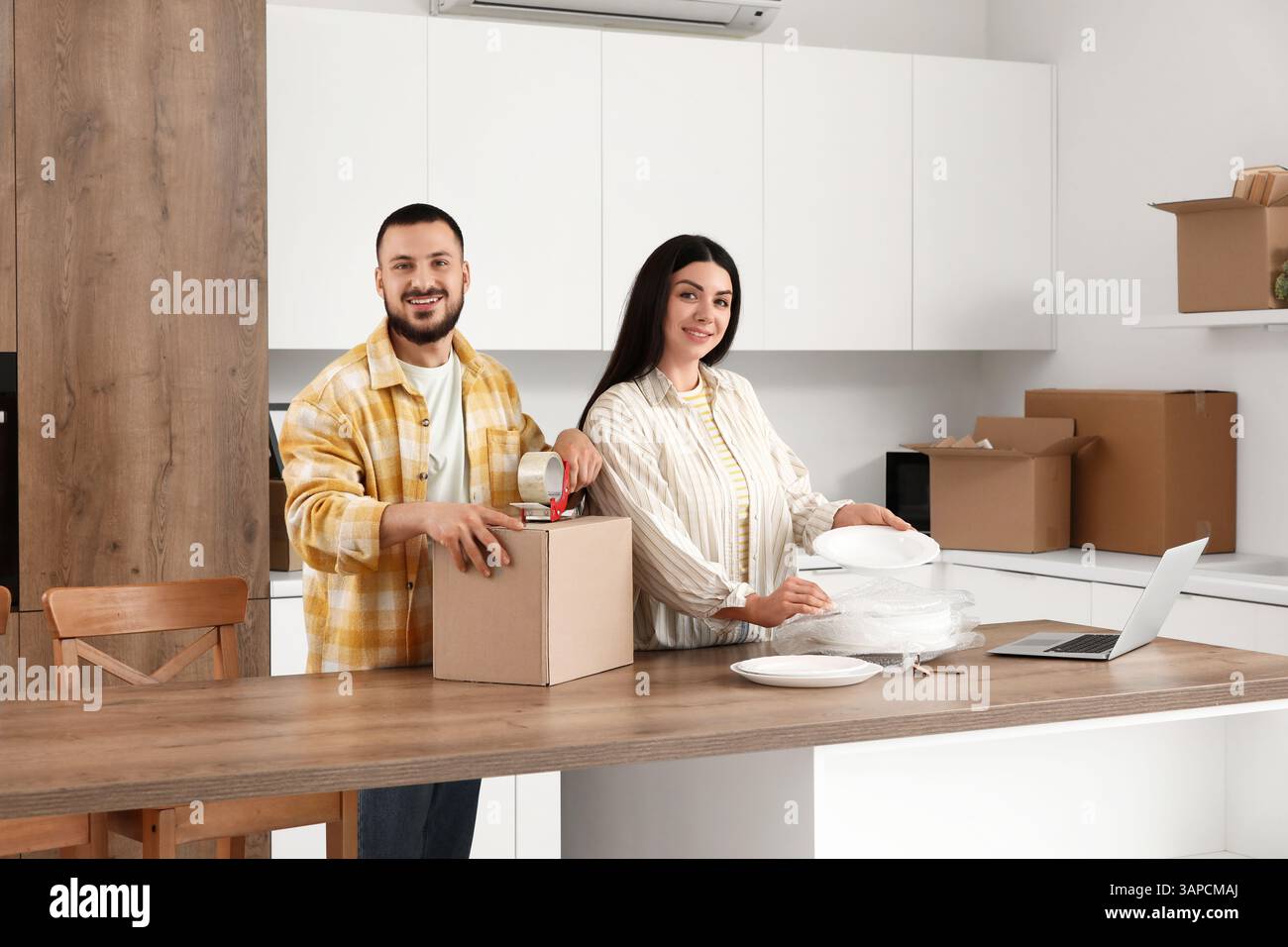 Happy young couple packing dishes in kitchen on moving day Stock Photo ...