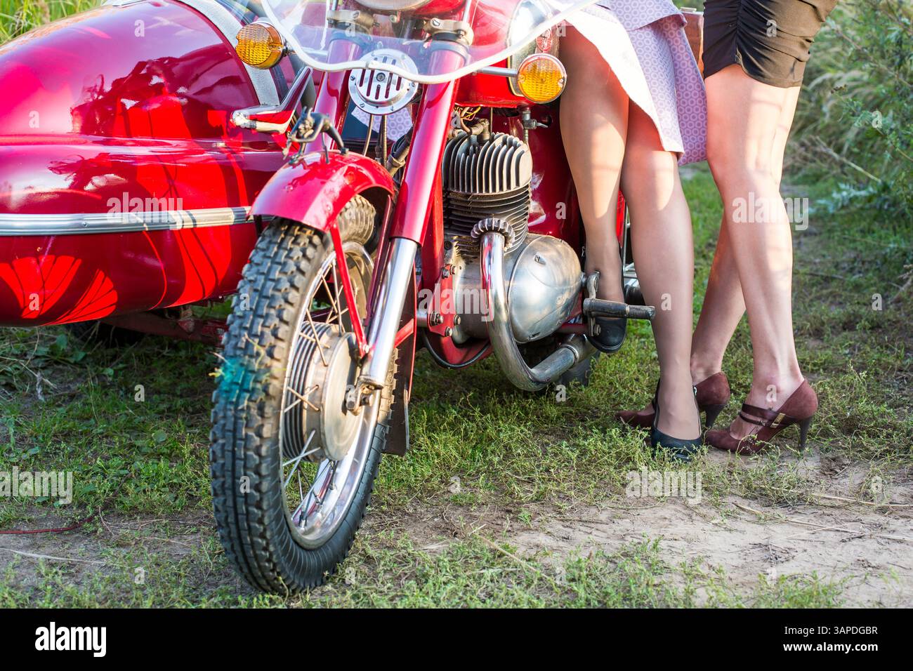 A woman is posing in front of a red motorcycle with a sidecar. The ...