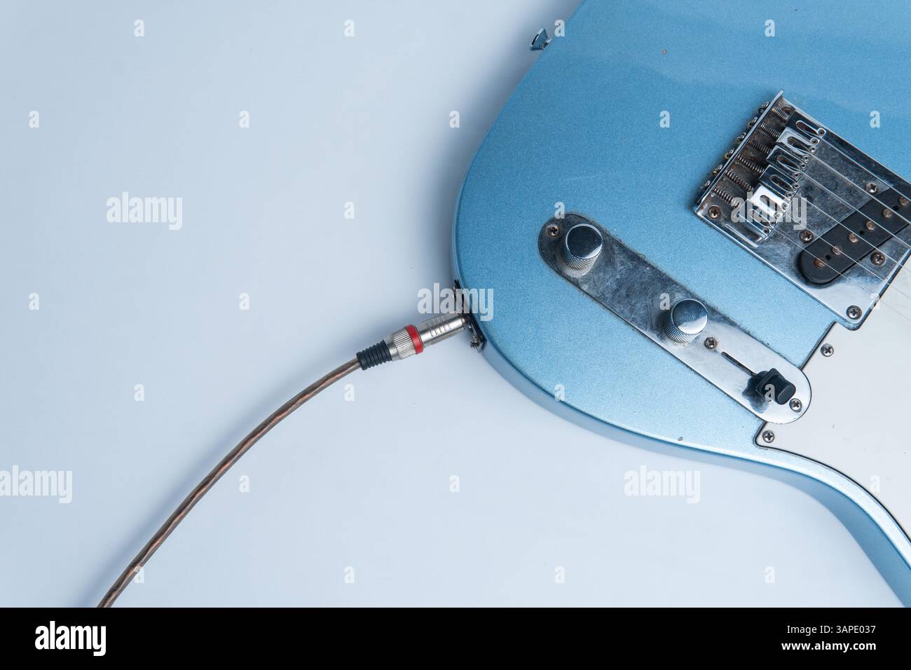A blue electric guitar with an audio cable plugged into its input jack ...