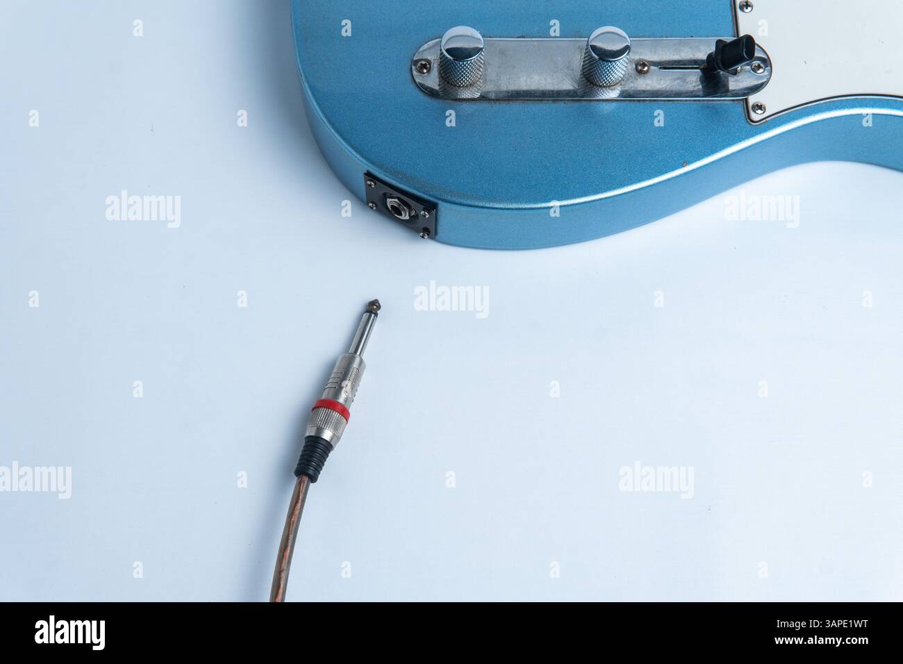 A blue electric guitar with an unplugged audio cable lying next to it ...