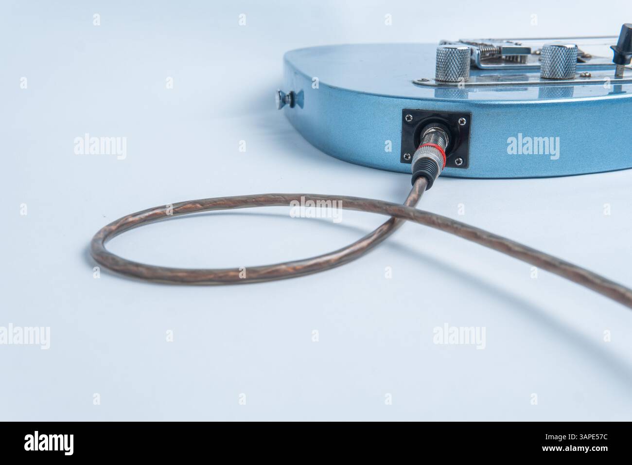 A blue electric guitar with an audio cable plugged into its input jack ...