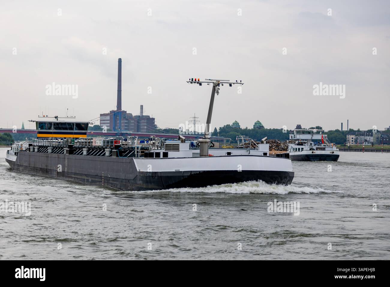 A cargo barge moves steadily along the Rhine river's current with an ...