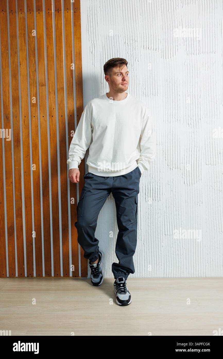 A stylish young man confidently displays a relaxed outfit in a vibrant ...