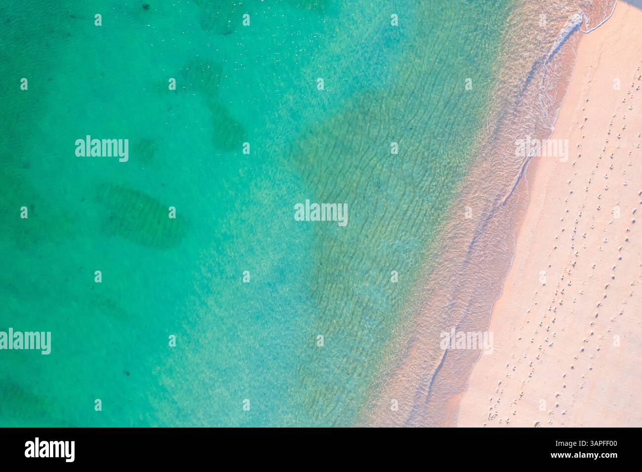 teal ocean waves on a pink sandy shore from above. Background texture ...