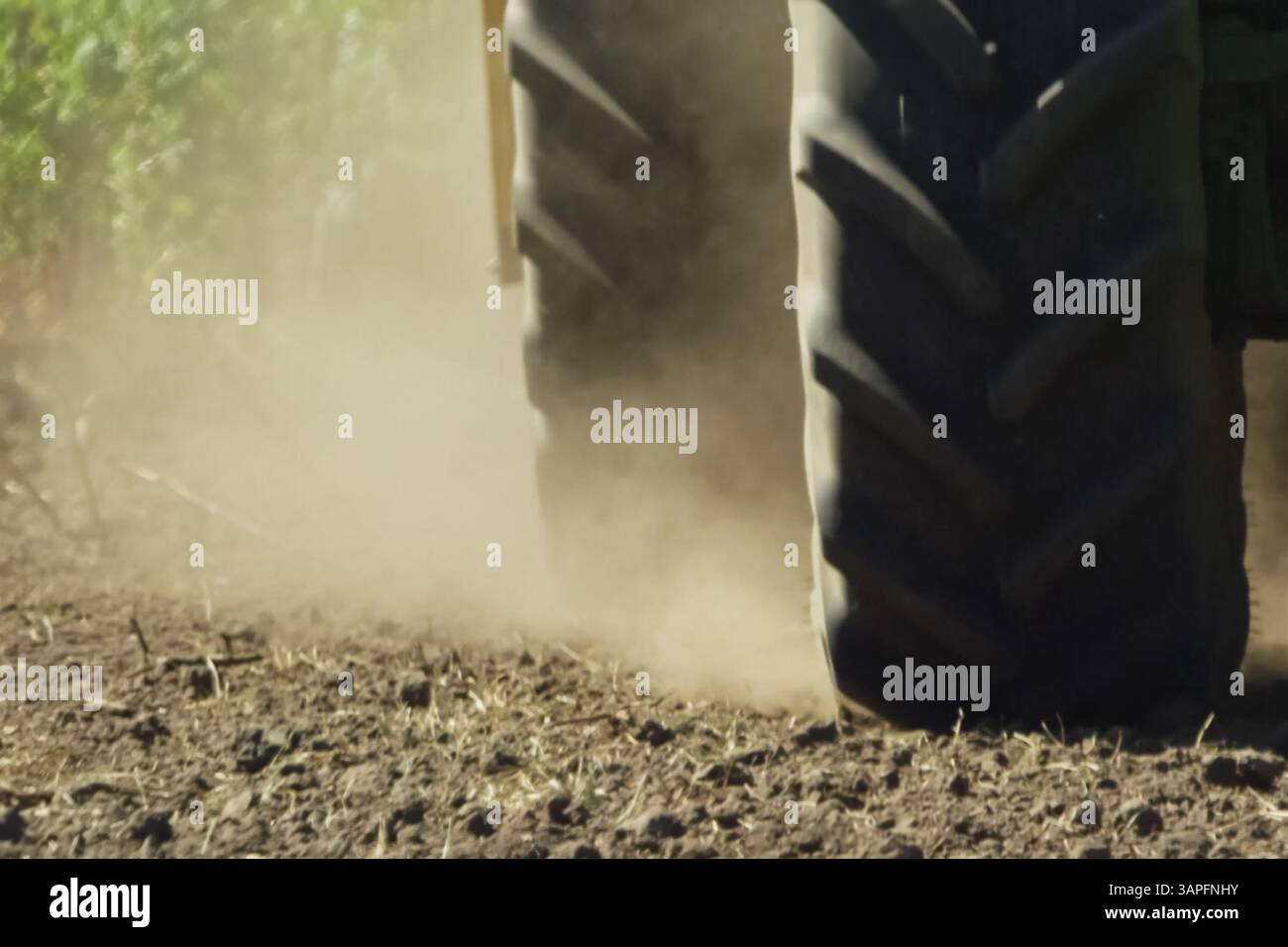the wheels of a tractor driving across a field. dust from the wheels ...