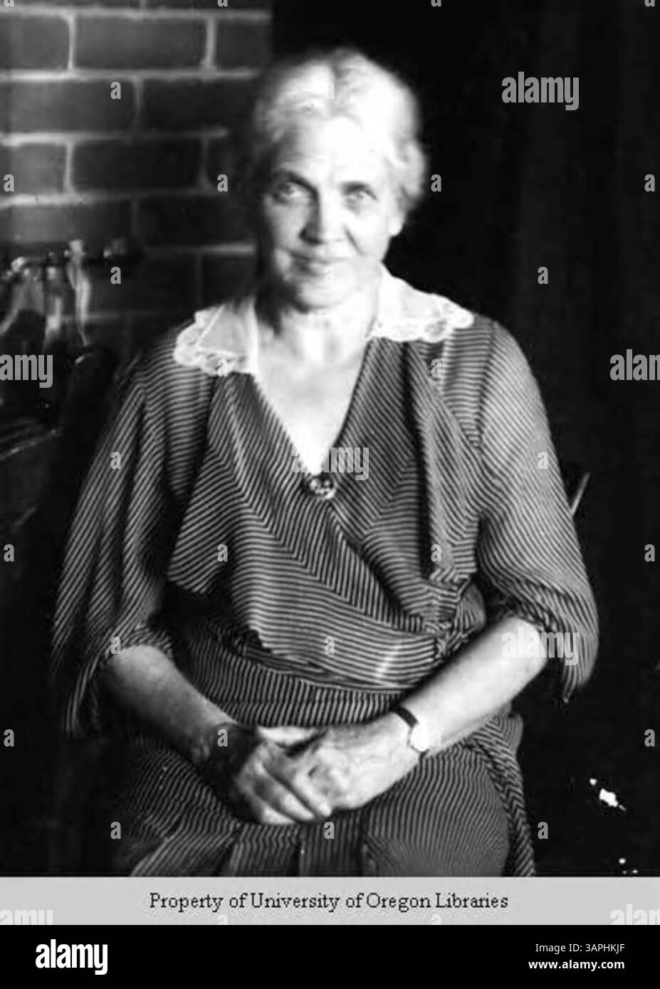 This photograph of Ms. Frost, seated and wearing a striped dress with a ...