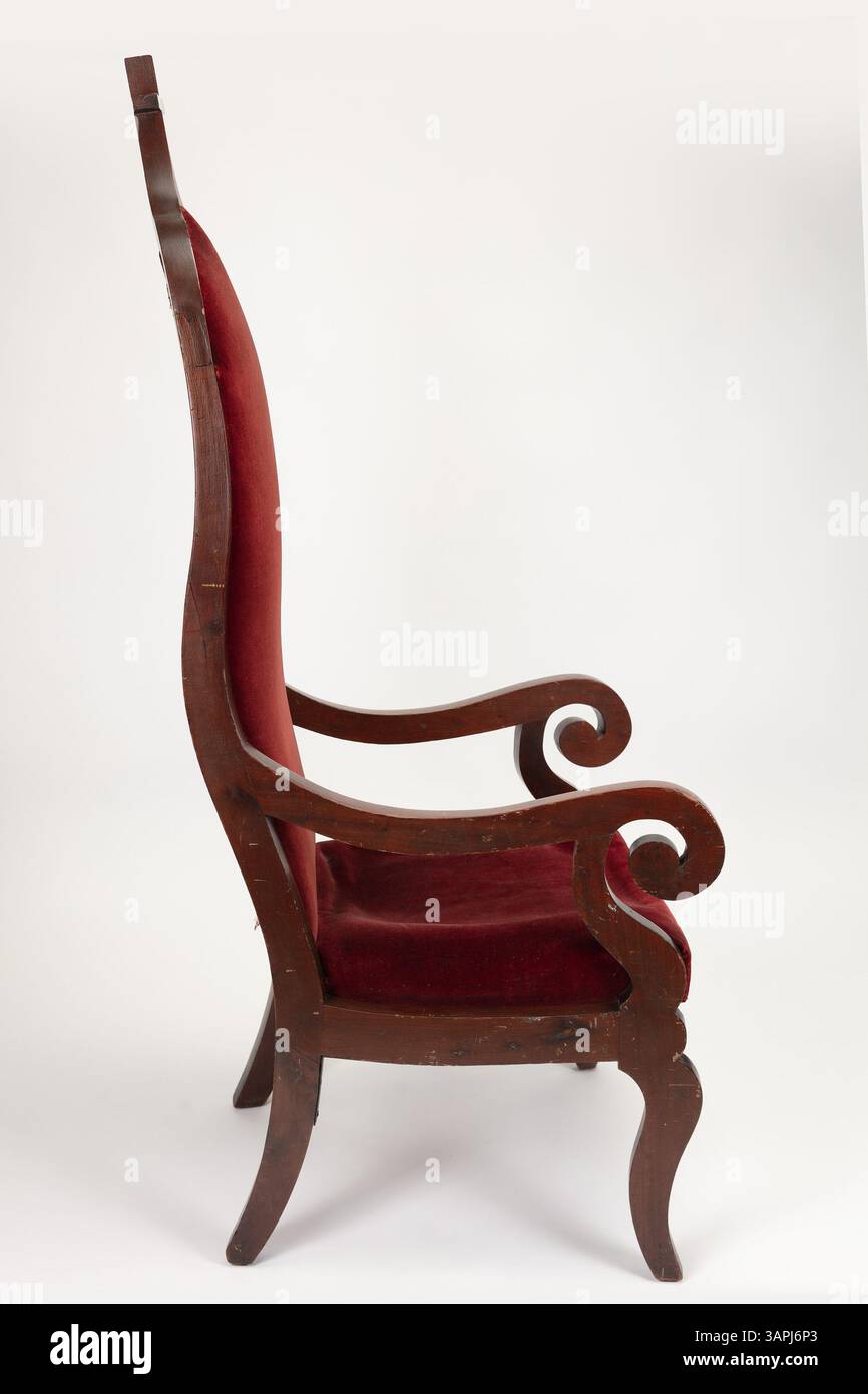 A high-backed priest's chair featuring a red velvet upholstered seat ...