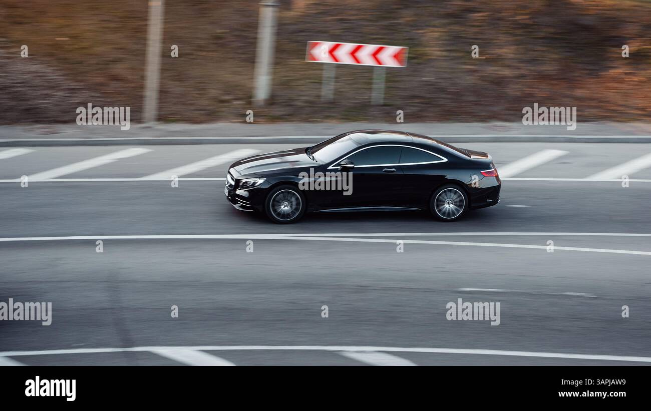 Black Mercedes coupe driving on a road. Side profile aerial view of ...