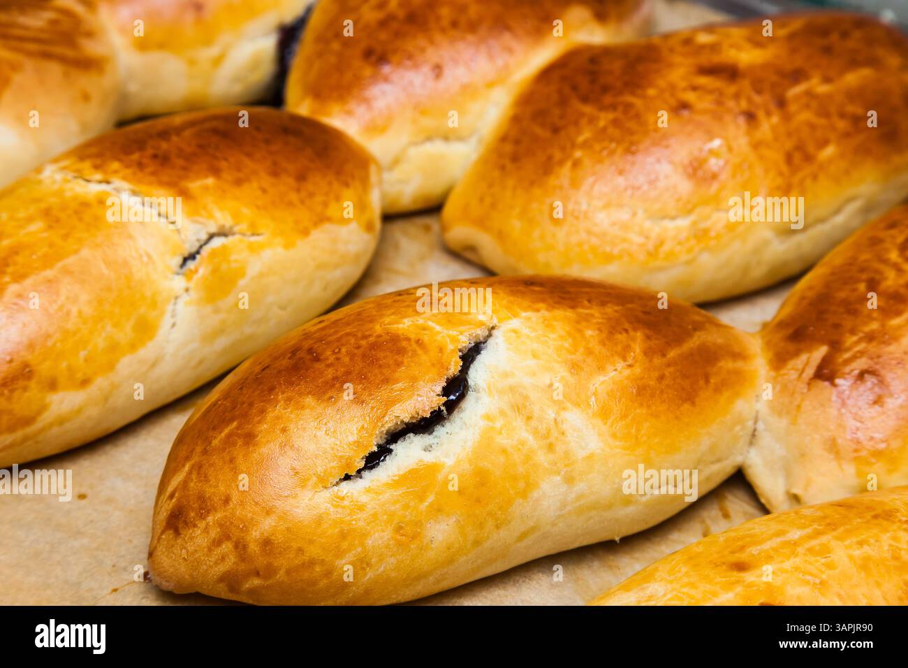 Baked buns stuffed with currant jam on parchment paper Stock Photo - Alamy