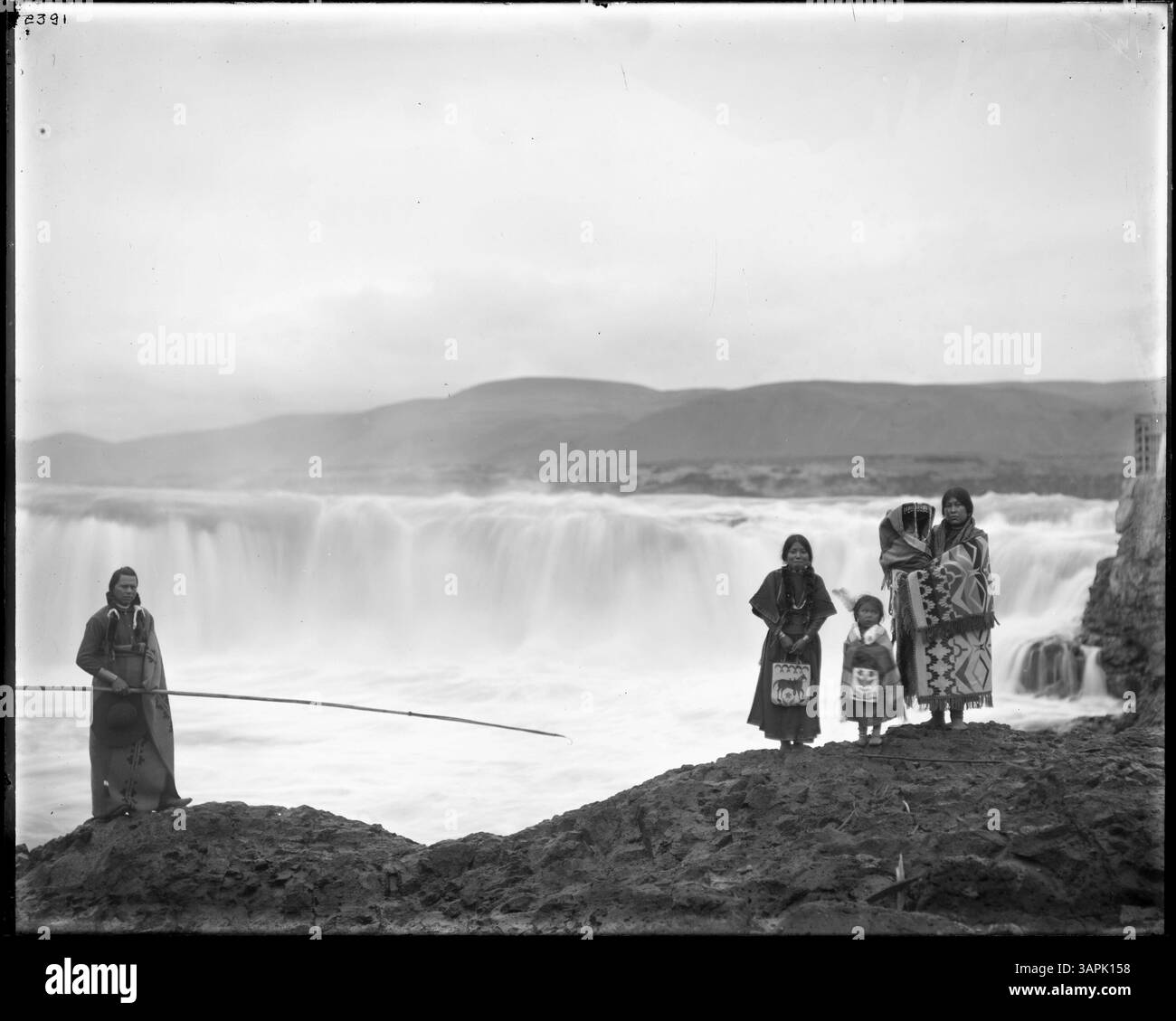A tribal family is pictured with Celilo Falls in the background. The ...