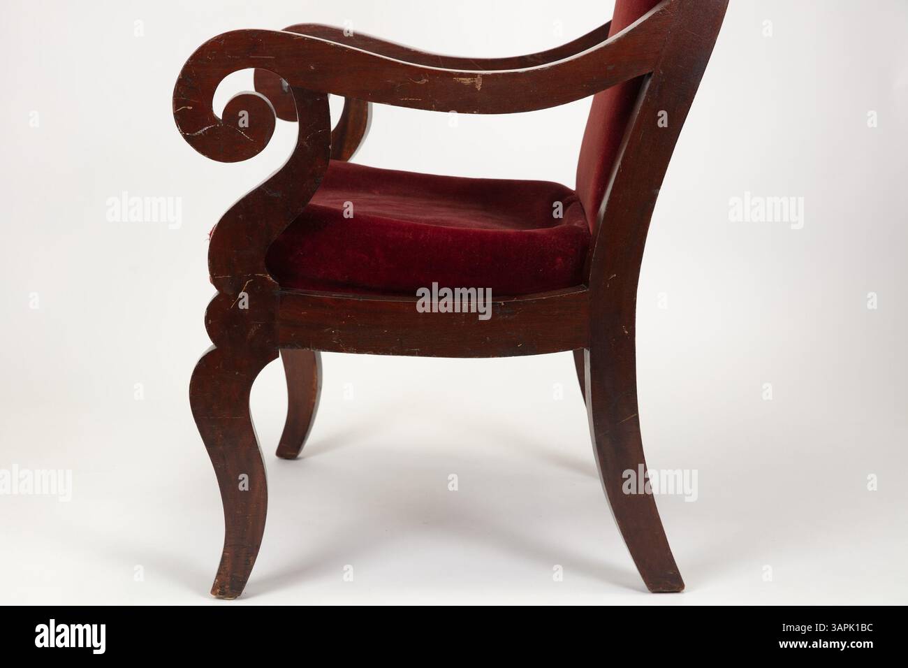A high-backed priest's chair featuring a red velvet upholstered seat ...