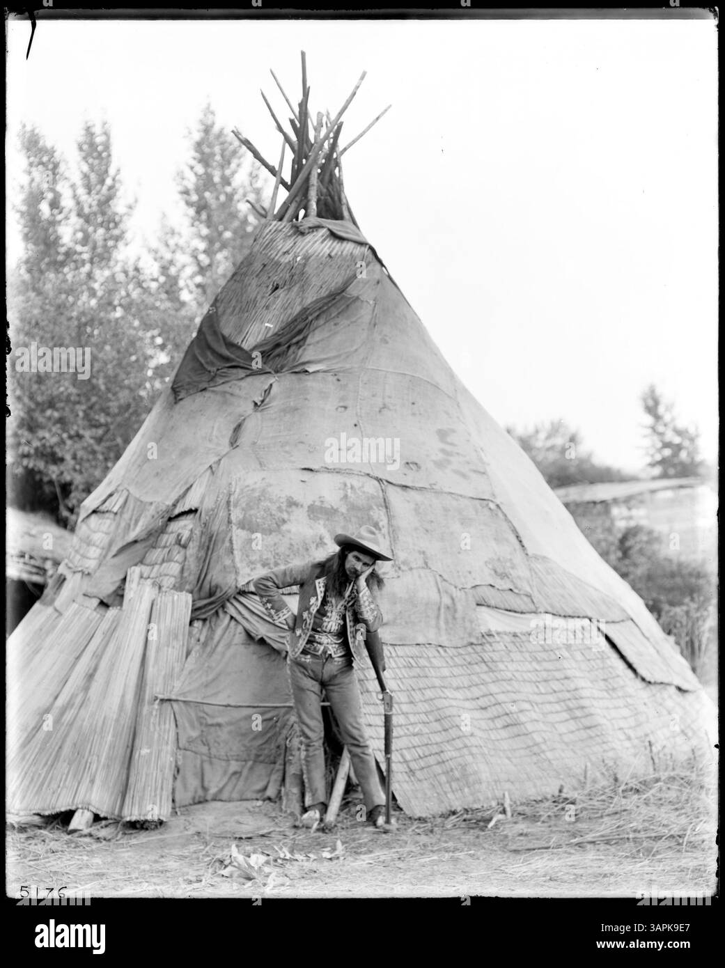 This photograph shows Arizona Bill with Native Americans outside a tipi ...