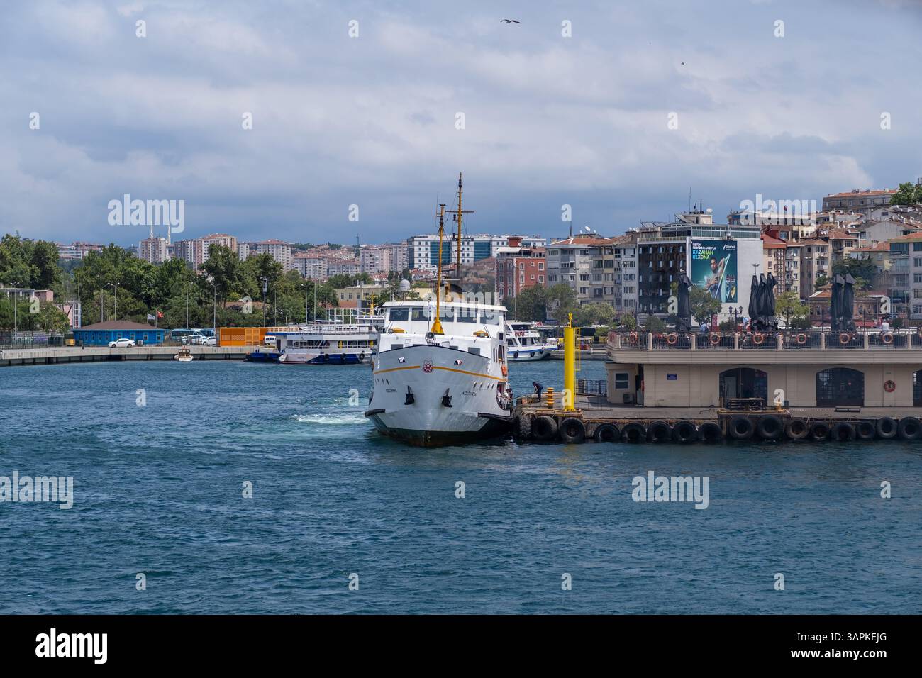 Bosphorus waterfront with ferry docking near city buildings under ...