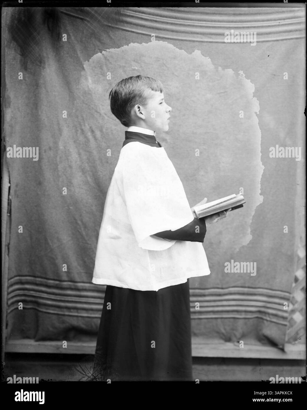 This photograph shows a choir boy dressed in vestments, showcasing the ...