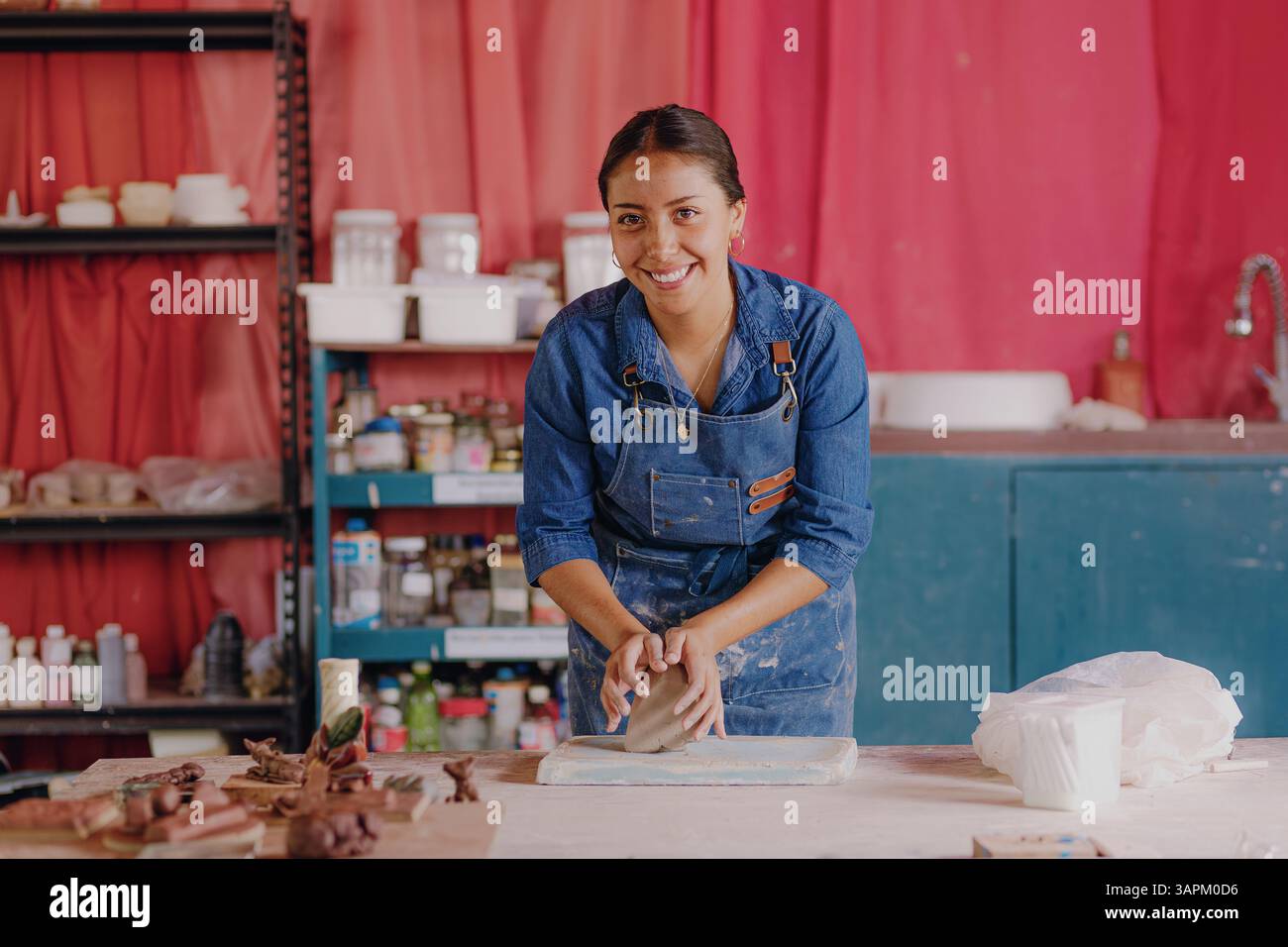 Mexican woman, 24, prepares clay in her artisan workshop before molding ...
