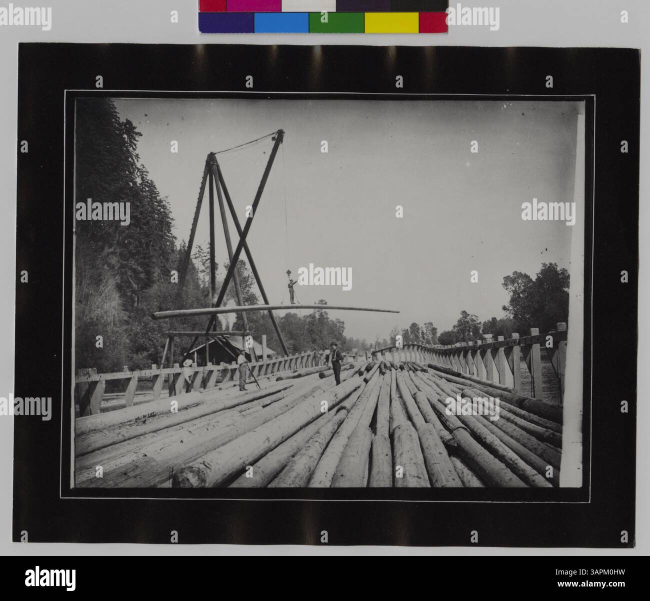 This print shows men constructing a log raft in a cradle, with one man ...