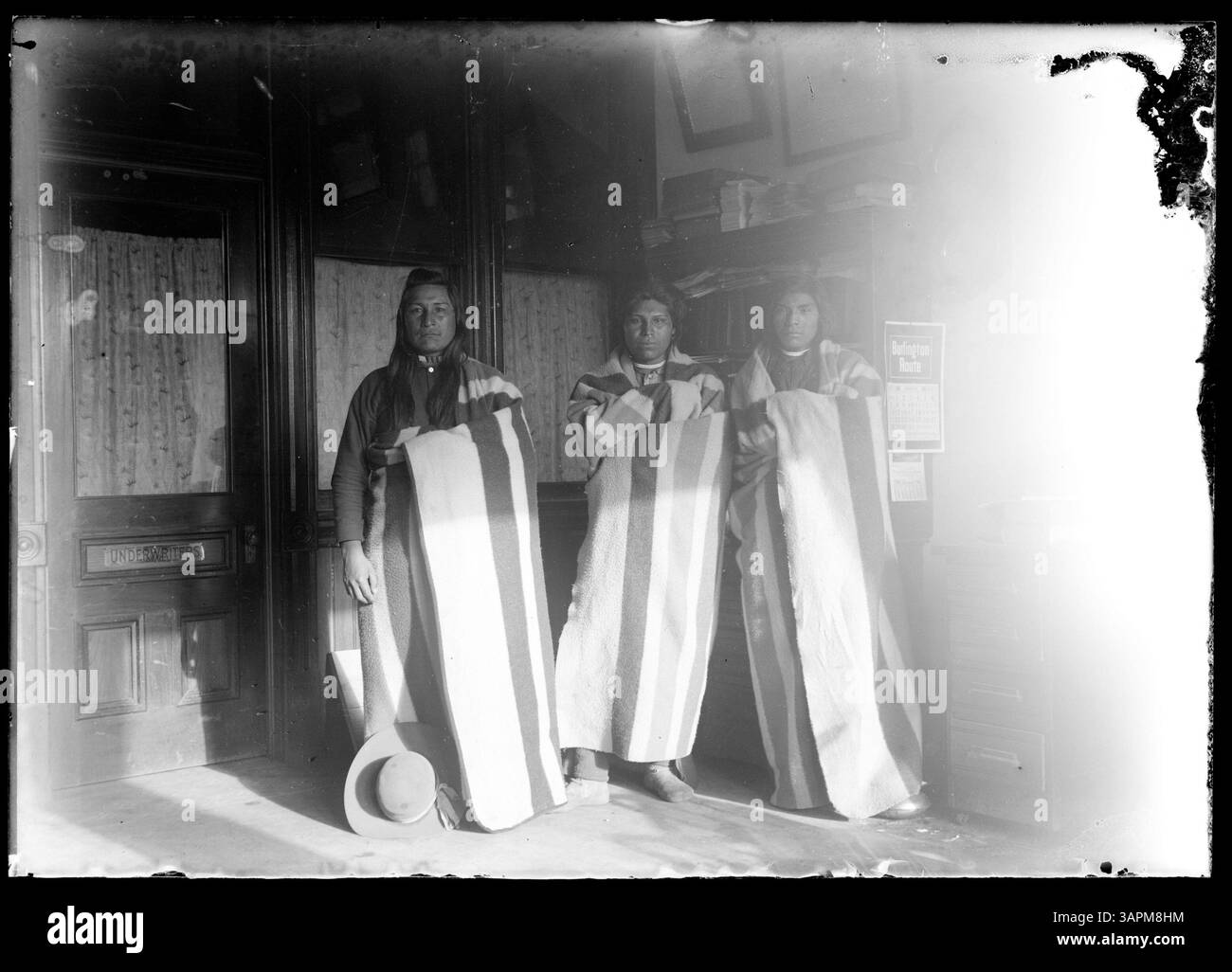 The photograph shows three Native American men posed indoors with ...